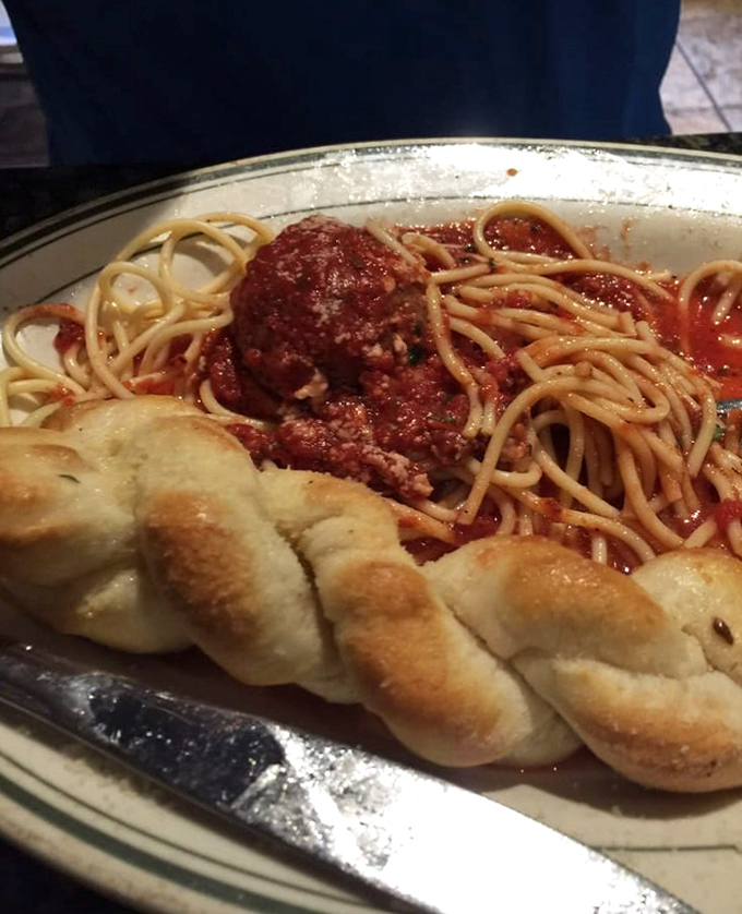 Spaghetti that would make nonna proud, with a perfectly twisted garlic knot standing guard beside a meatball worthy of its own zip code.
