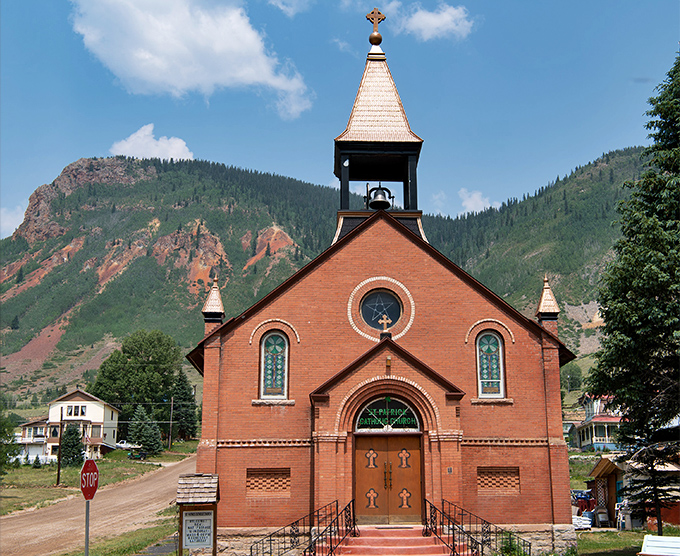 St. Patrick Catholic Church's brick beauty stands as a testament to miners' faith, its stained glass windows catching mountain light like spiritual prisms.