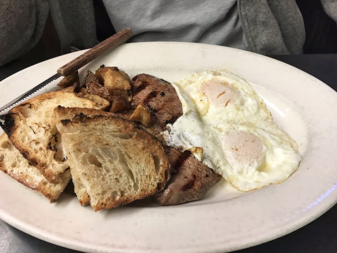 The breakfast trinity: perfectly cooked eggs, golden home fries, and toast substantial enough to support your morning ambitions.