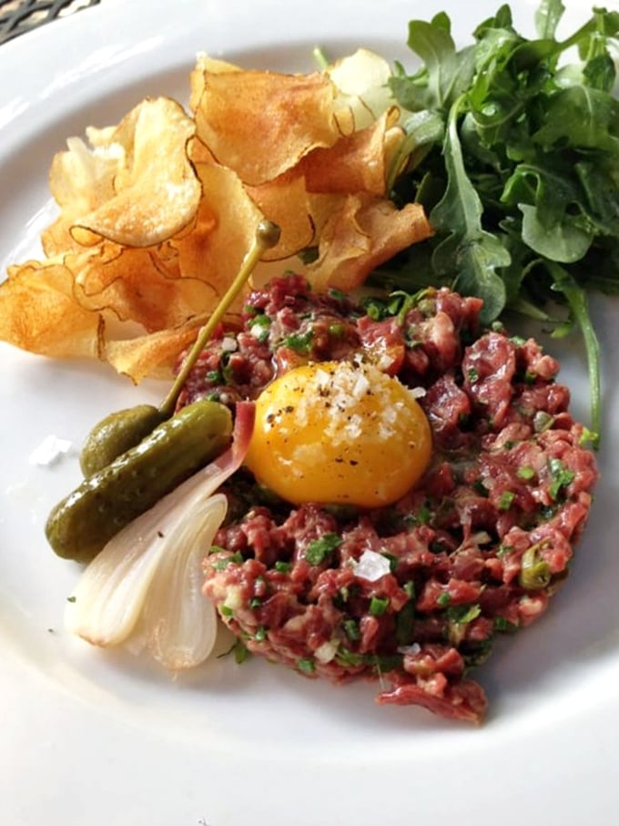 Steak tartare elevated to art form &ndash; the vibrant egg yolk crowning hand-cut beef is a flavor bomb waiting to detonate.