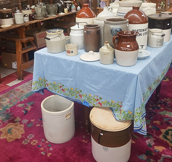 A blue-clothed table presents a stoneware symphony, each crock and jug silently testifying to generations of practical use.