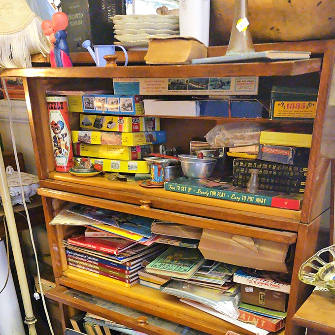 Vintage games and collectibles stack like archaeological layers, each shelf revealing another era's idea of entertainment gold.
