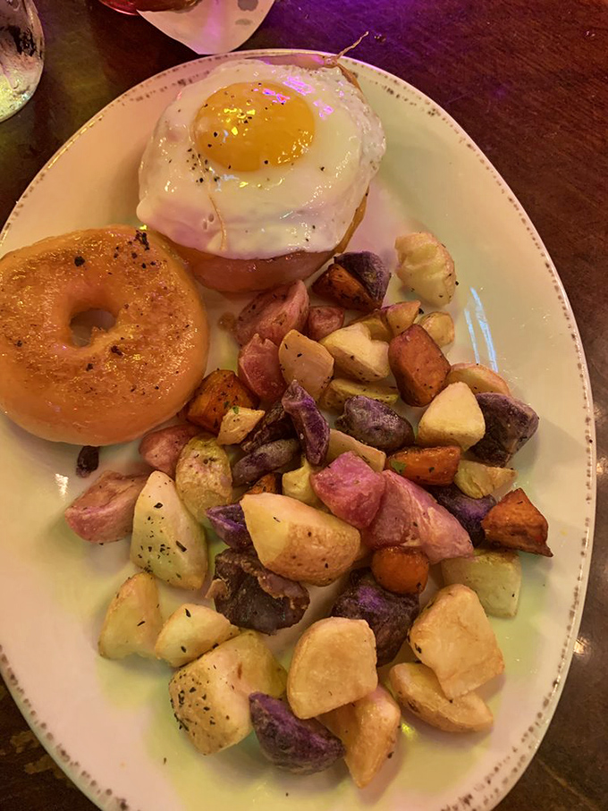 A perfectly fried egg crowns colorful roasted potatoes like a morning sunrise. Simple perfection that proves breakfast is the day's most important masterpiece.