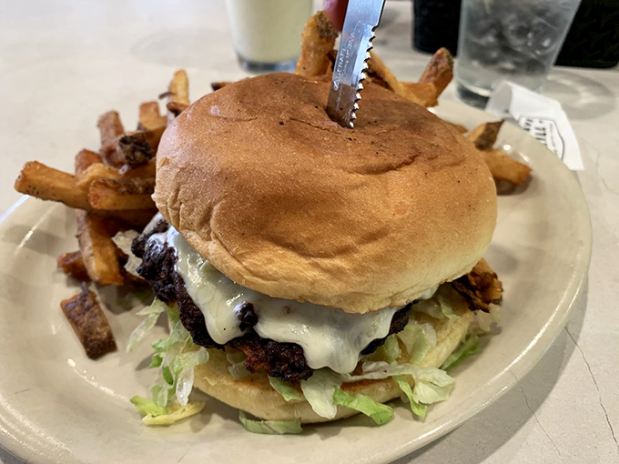 This towering burger situation comes loaded with crispy onion strings piled so high it requires strategic planning to eat.