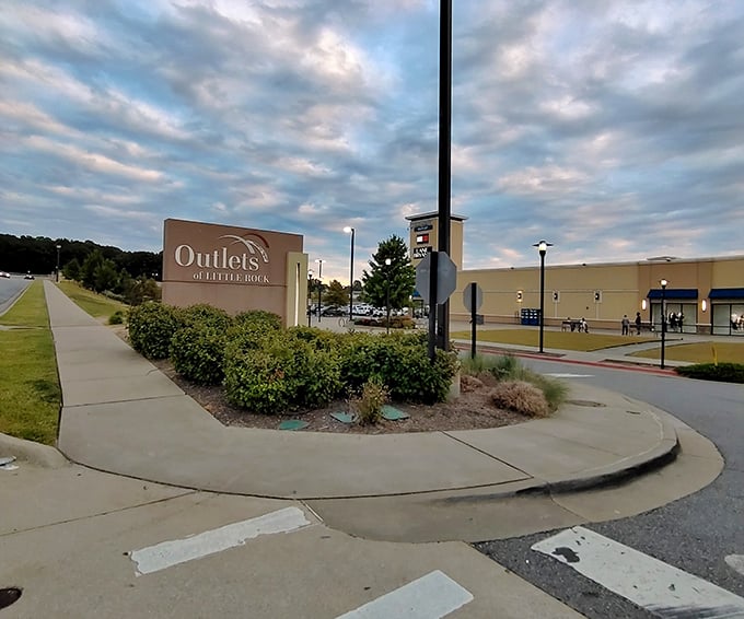 The welcoming entrance sign to Outlets of Little Rock stands sentinel at dusk, promising retail adventures just beyond the landscaped perimeter.