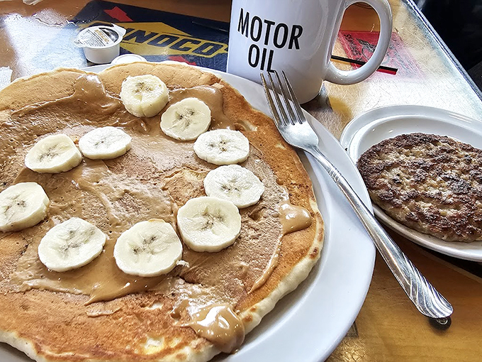 Pancakes so perfectly golden they belong in Fort Knox, topped with bananas that didn't sacrifice themselves in vain. The "MOTOR OIL" mug contains coffee, we hope.
