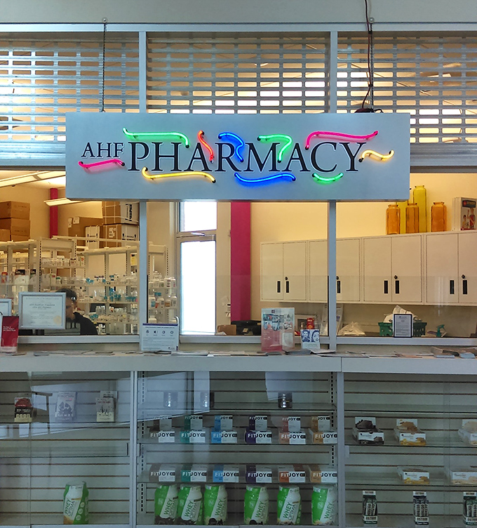 The colorful neon pharmacy sign illuminates a corner where healthcare meets affordability, proving medicine doesn't have to break the bank.