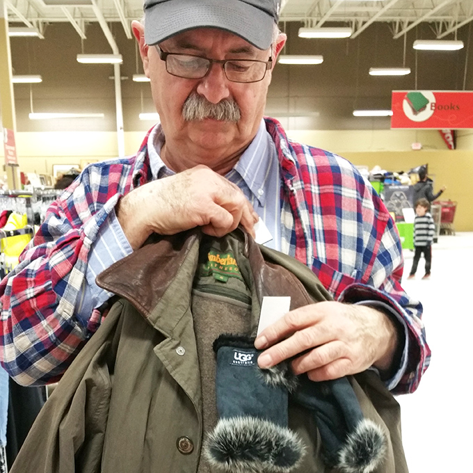 The thrill of discovery! This shopper examines a winter coat with the focused intensity of an archaeologist uncovering ancient artifacts.