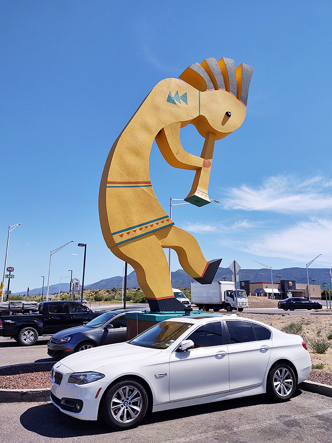 Parked BMWs look like toy cars beneath this golden flute player, offering perfect scale for the "I swear it was THIS big" fishing story.