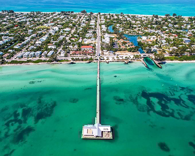 Anna Maria's pristine white sand beach stretches endlessly, with that iconic pier reaching into water that changes color with the clouds.