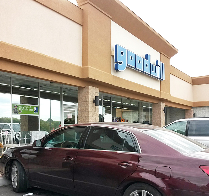 Goodwill's familiar blue signage stands out against the tan building. Inside this unassuming exterior lies a labyrinth of potential finds.