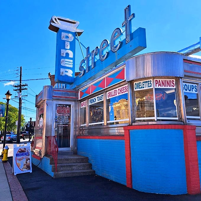 Main Street Diner's electric blue facade and vintage signage pop against the sky like a Technicolor dream. Those window advertisements promise a world of comfort inside.