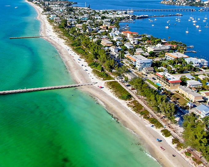 The Gulf waters here shimmer in every shade of blue imaginable, from turquoise shallows to deep sapphire where boats drift lazily.