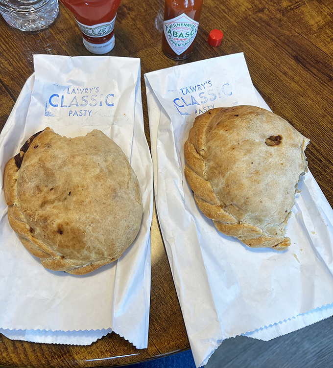Two classic pasties, wrapped and ready for their close-up. The paper bags are just formalities—these won't last long enough to need packaging.