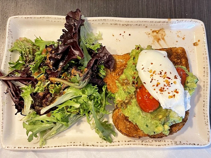 Avocado toast with a poached egg and mixed greens&mdash;proof that trendy brunch items taste better when actual cooks make them.