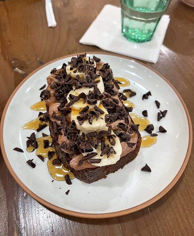 Banana bread elevated to art form with chocolate shavings, caramelized bananas, and what appears to be a drizzle of pure happiness. Dessert for breakfast? Absolutely.