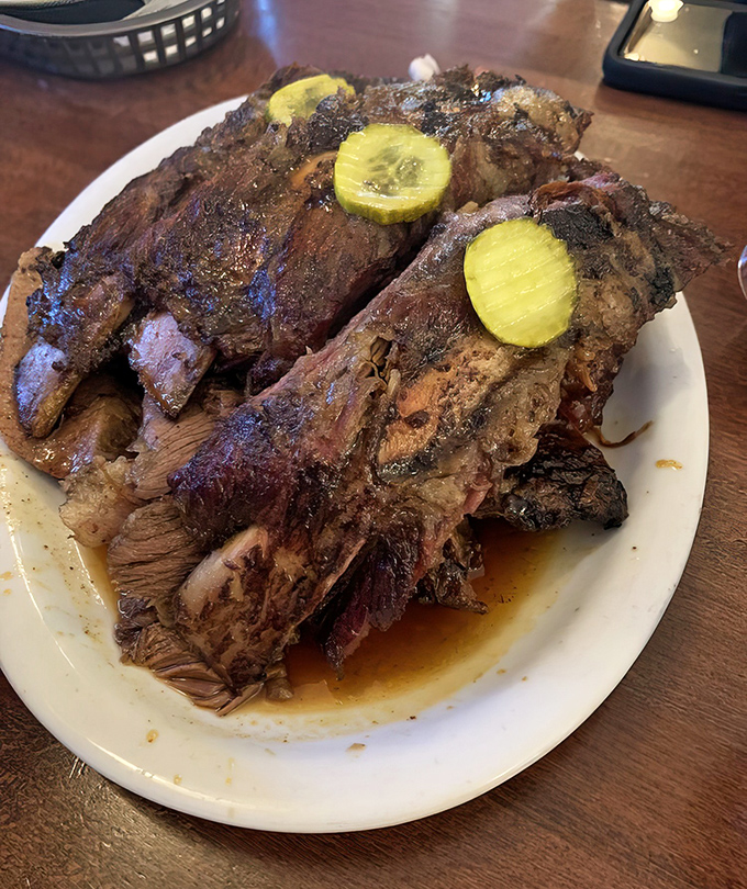 These beef ribs aren't just dinner—they're prehistoric satisfaction with pickle coins standing guard. Fred Flintstone would weep with joy.