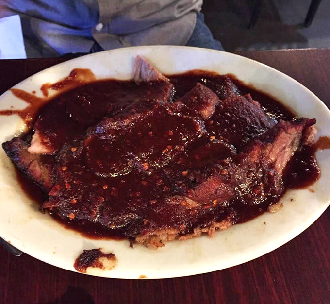 Brisket so deeply lacquered with sauce and smoke, it looks like it's wearing a delicious mahogany suit to a very important flavor meeting.