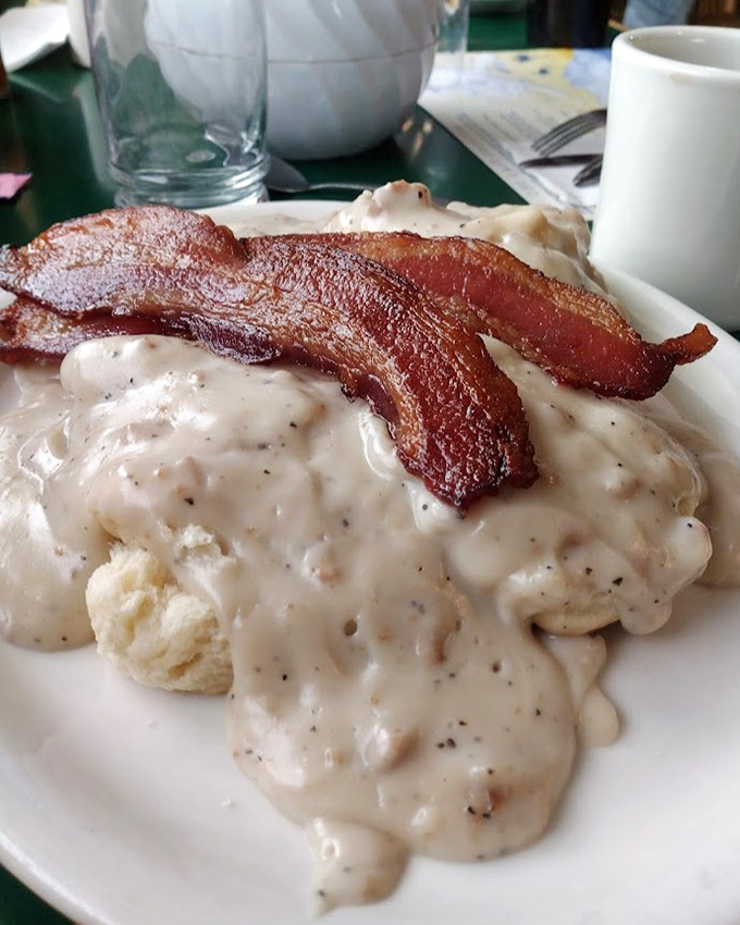 Biscuits drowning happily in a sea of peppery gravy with bacon standing guard&mdash;breakfast architecture at its most delicious.