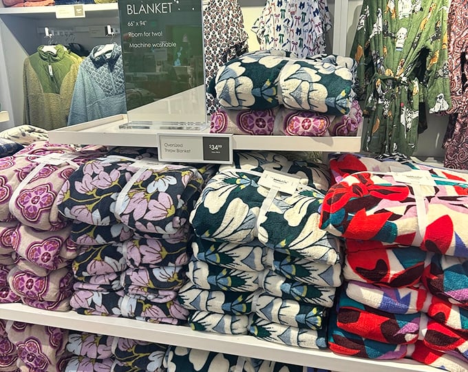 Blankets stacked like cozy possibilities, each one whispering promises of perfect temperature control and Netflix marathon comfort levels.