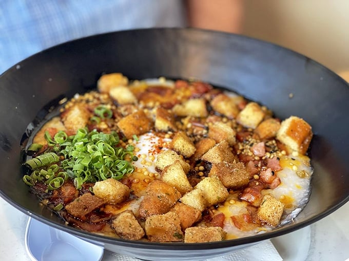 Breakfast congee that's had a glow-up &ndash; crispy bits, fresh herbs, and an egg that's just waiting for its Instagram moment.