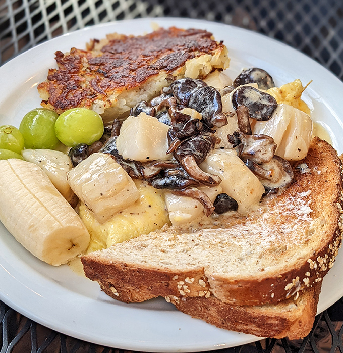 Breakfast alchemy: perfectly caramelized hashbrowns, mushroom-laden toast, fresh fruit, and what appears to be banana slices create morning magic on a plate.