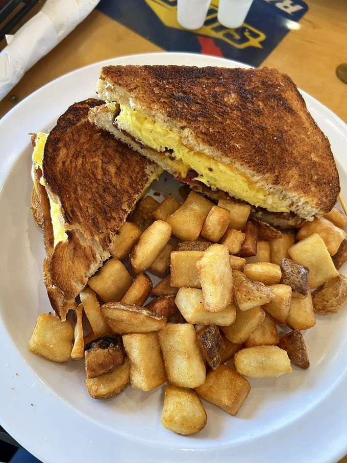 Breakfast sandwiches should be knighted for their service to humanity. This golden-grilled masterpiece with home fries proves morning meals deserve evening respect.