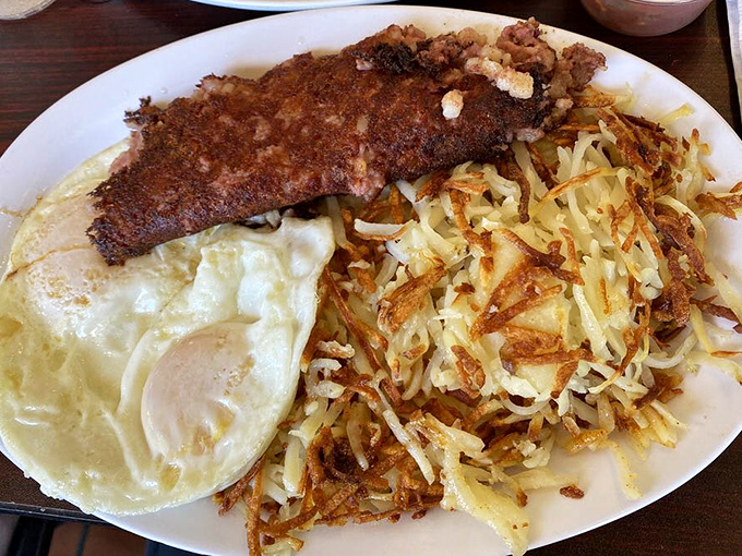 The breakfast holy trinity: perfectly crispy hash browns, eggs with just-right yolks, and country fried steak that could make a vegetarian question their life choices.