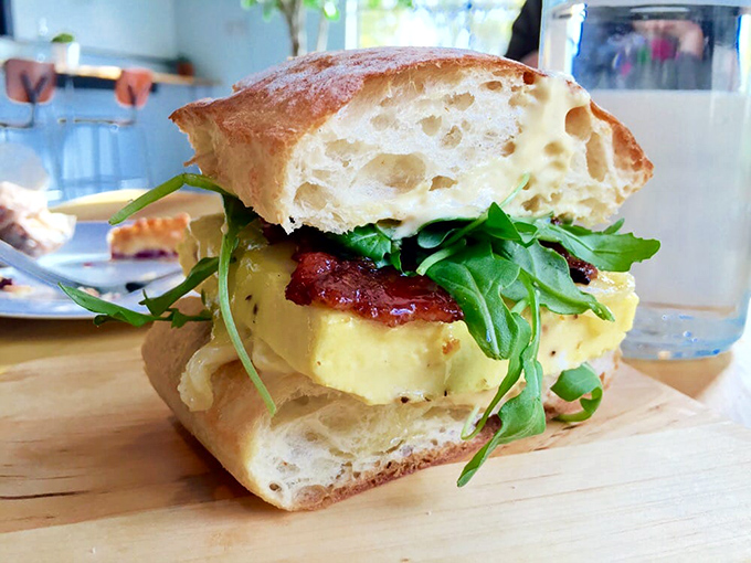 The breakfast sandwich in its natural habitat&mdash;ready to be devoured. That perfect cross-section reveals layers of egg, bacon, and greens in harmonious balance.