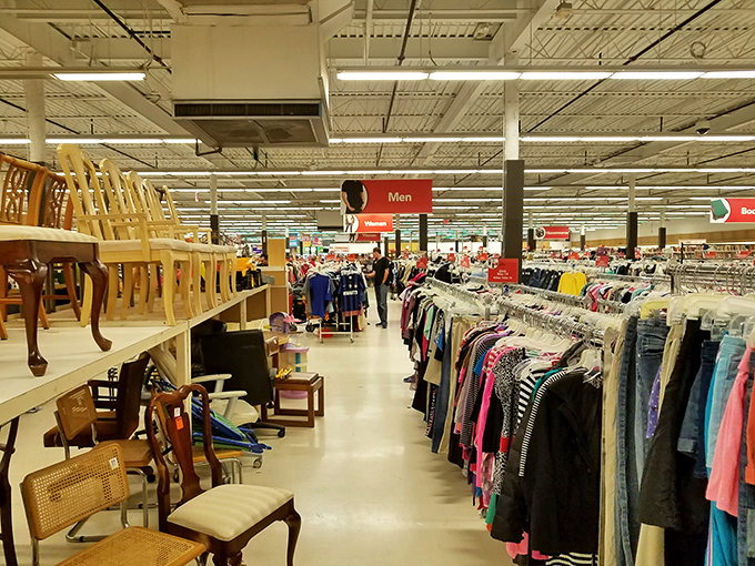 Wooden chairs perch like hopeful contestants on a dating show, while clothing racks stretch toward retail infinity.