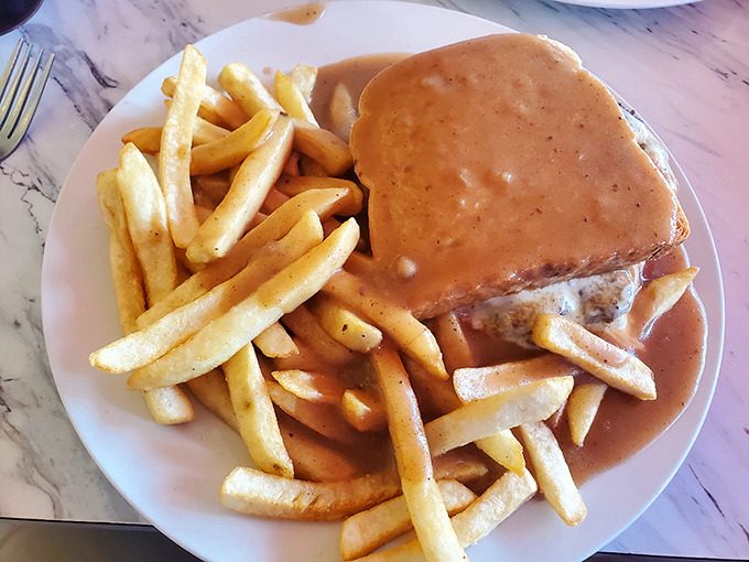 A burger smothered in gravy that says, "Diet starts tomorrow." Those fries are just begging to be dragged through that savory pool.