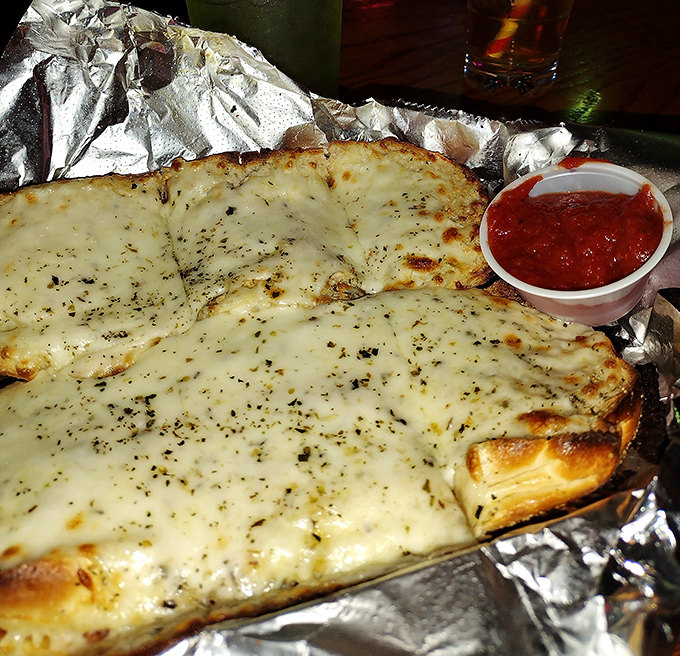 The legendary cheesy garlic bread arrives like a celebrity, demanding attention with its golden crust and side of marinara for dipping.