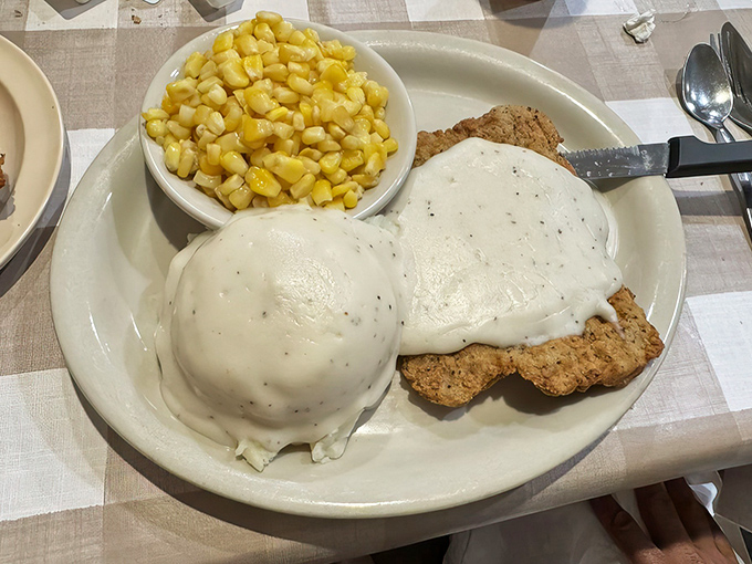 Country fried steak smothered in gravy with a side of corn—the kind of plate that makes you want to hug the cook and take a nap afterward.