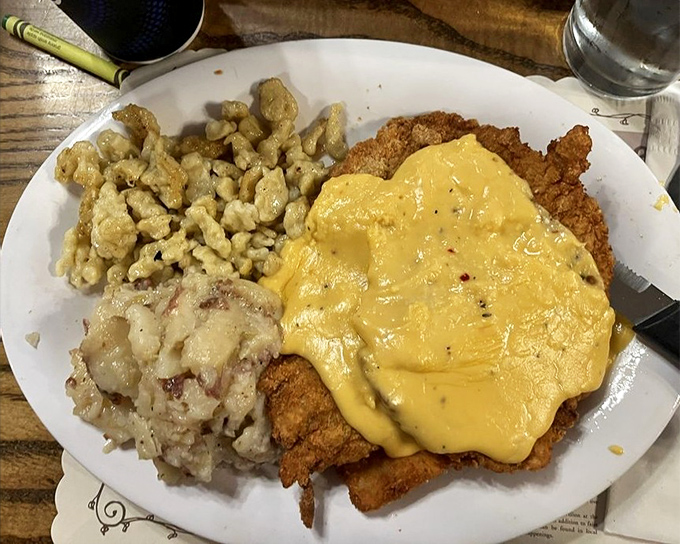 Schnitzel so golden it deserves its own Olympic medal, smothered in cheese sauce with sides that know their supporting role perfectly.