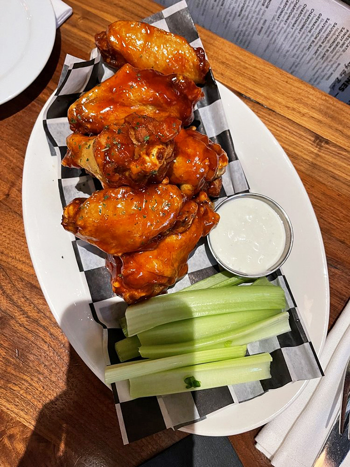 Wings that make you question why you ever settled for less – glistening with sauce and accompanied by cooling celery sticks for that perfect balance.