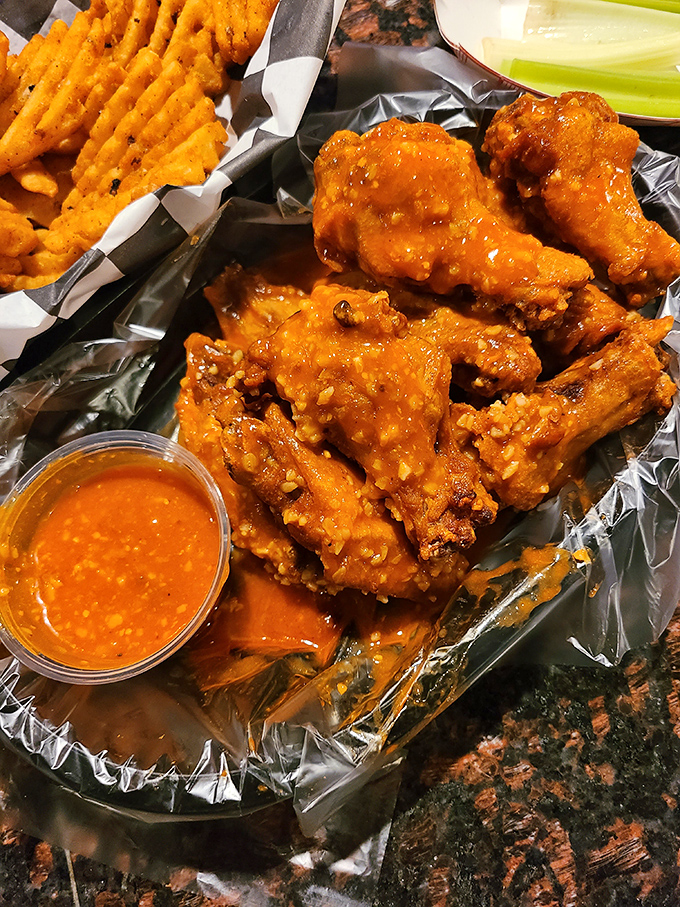 Wings that have clearly earned their "Famous" title, glistening with sauce and promising a flavor explosion. The waffle fries aren't just a side&mdash;they're essential sauce-delivery vehicles.
