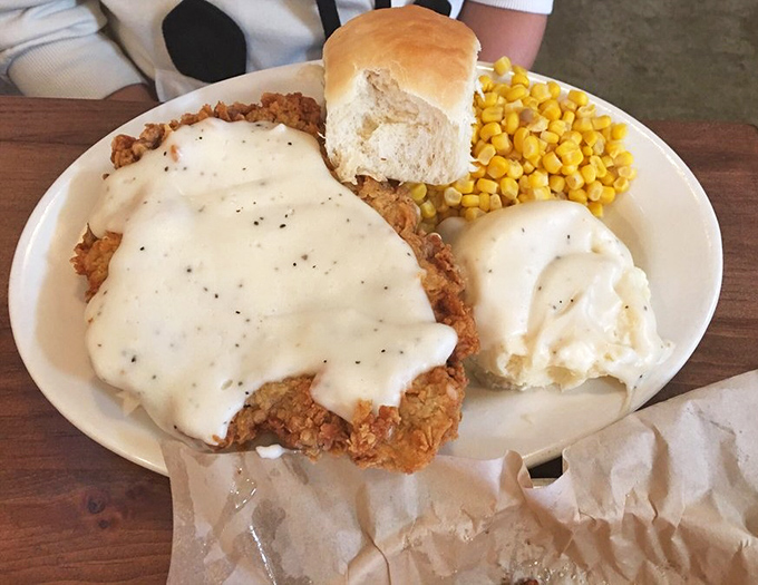 Chicken fried steak smothered in country gravy alongside mashed potatoes and corn&mdash;the holy trinity of heartland comfort.