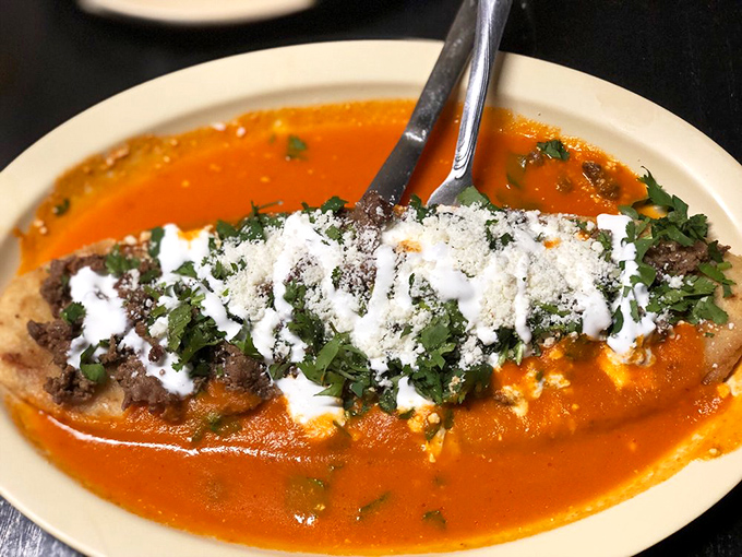 A chile relleno bathed in vibrant sauce with dual personalities – one side green, one side red, both sides absolutely magnificent.