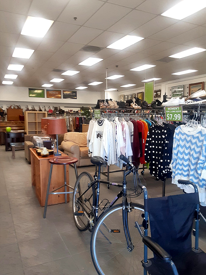 A vintage bicycle stands guard among clothing racks and furniture finds. Someone's transportation treasure is about to become your conversation piece.