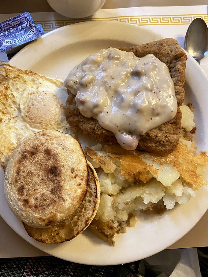 Country-fried steak smothered in peppery gravy alongside golden hashbrowns and English muffins—a plate that says "everything's going to be okay" in food form.