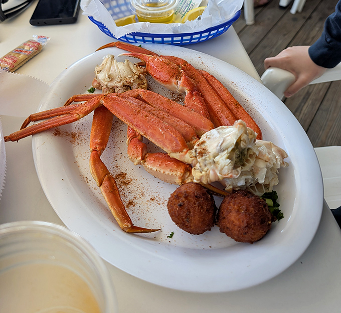 Snow crab legs sprawled majestically across the plate like they're sunbathing on their own private beach, with hush puppies standing guard.