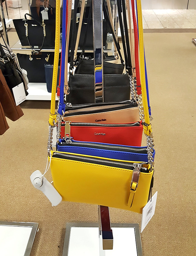 A rainbow of crossbody bags dangles like fashionable fruit, tempting shoppers to add "just one more" to their collection. Resistance is futile.