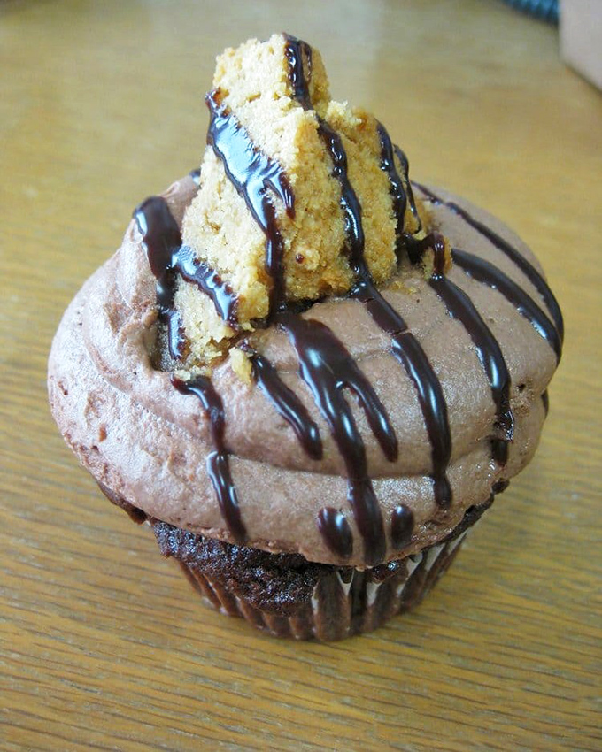 Chocolate cupcake topped with what can only be described as frosting nirvana. That cookie garnish isn't just decoration—it's the crown jewel of this dessert kingdom.