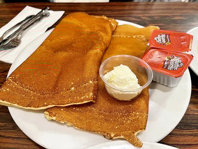 These golden pancakes arrive looking like edible sunshine, ready for their butter and jam close-up.