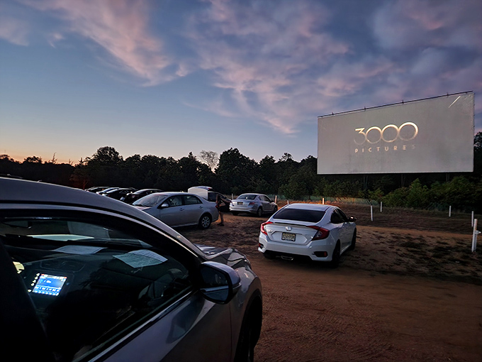 As darkness embraces the lot, the screen illuminates with vibrant color. Modern projection meets timeless tradition in this twilight tableau.