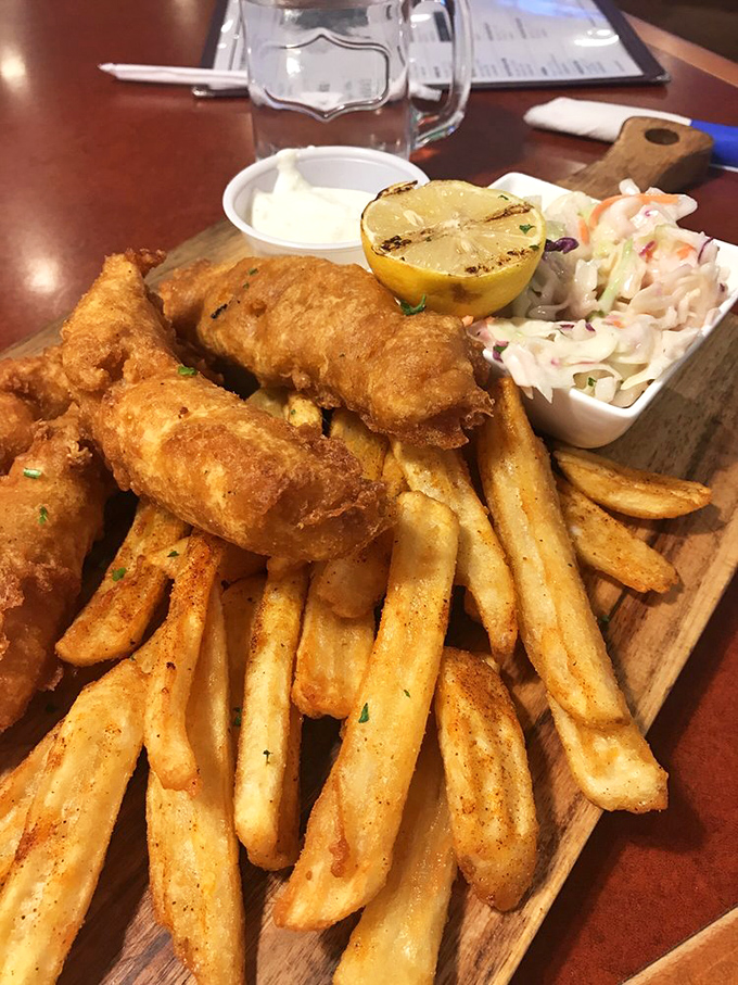 Fish and chips that would make a British pub proud, served on a rustic wooden board with house-made slaw and a grilled lemon for that chef's touch.