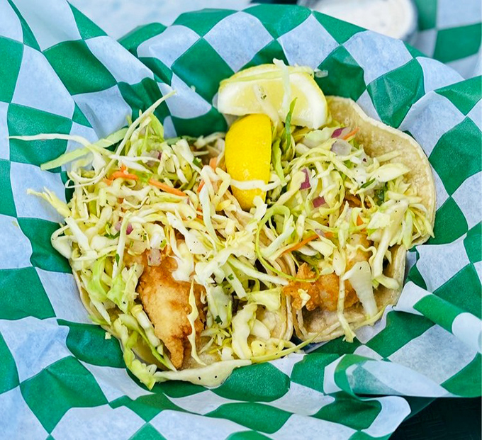 Fish tacos done right—crispy, fresh, and nestled in a checkered paper cradle. The slaw-to-fish ratio is what mathematicians call "the golden ratio of deliciousness."