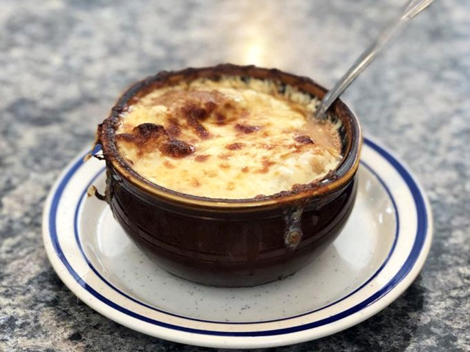 The French onion soup arrives wearing its signature cheese beret, bubbling with personality and ready for its delicious close-up.