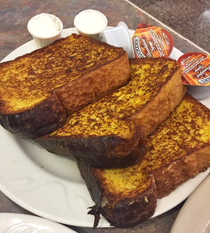 French toast so thick it needs its own zip code. Golden-brown slices that absorbed custard like they were training for an Olympic event.