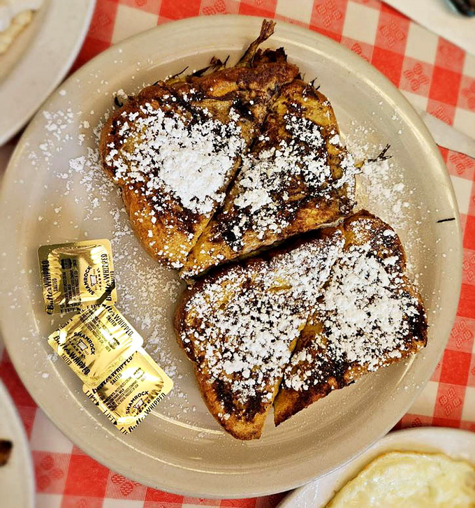 French toast dusted with powdered sugar &ndash; simple pleasures elevated to art form. The butter packets standing by like eager understudies waiting for their moment.